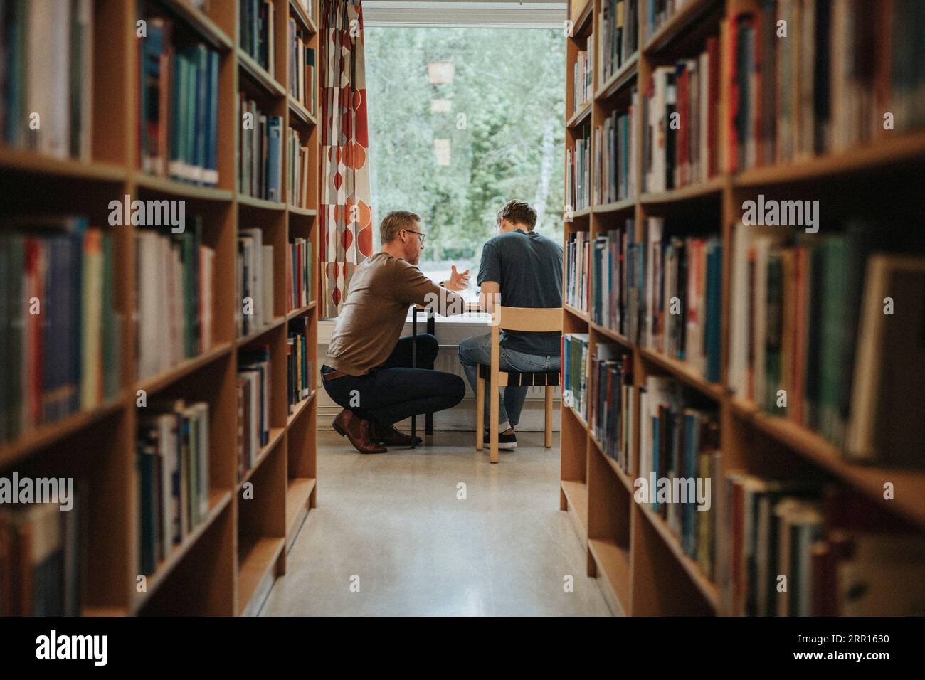 Professor explaining student in library at university Stock Photo - Alamy