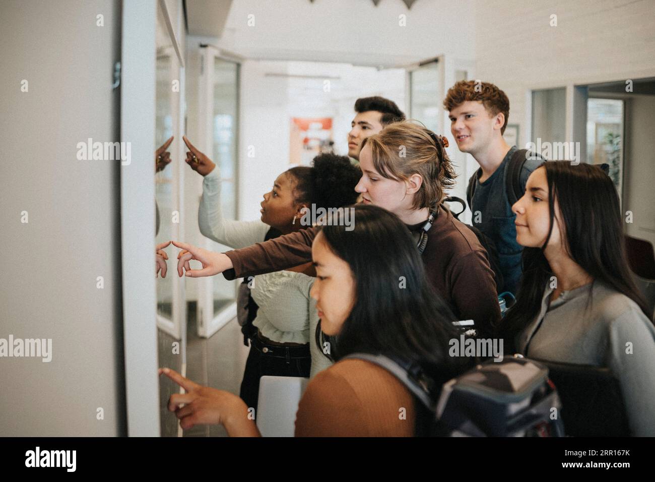 Multiracial students checking result on bulletin board in university ...