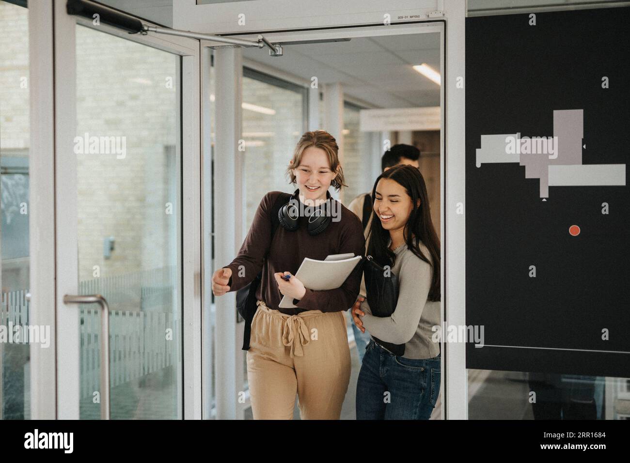 Happy student with friend entering classroom in university Stock Photo ...