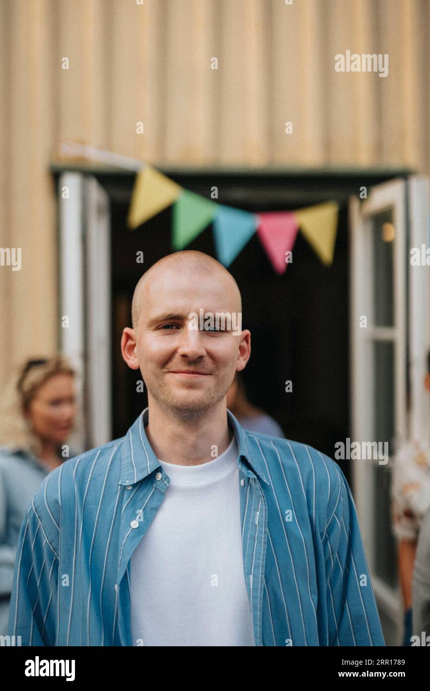 Portrait of smiling young man with shaved head during dinner party at ...