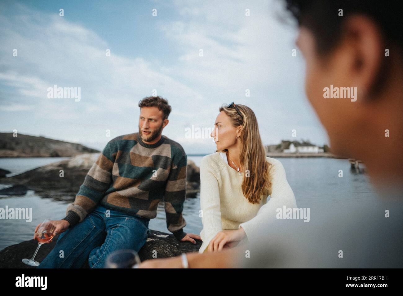 Man and woman talking with each other while sitting on rock near lake ...