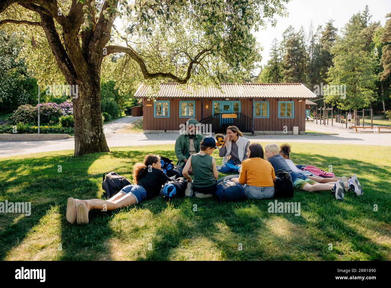Kids having fun while enjoying with camp counselors on grass at summer ...