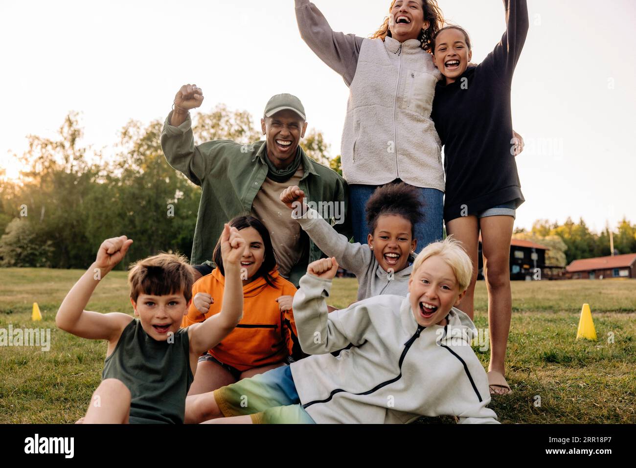 Cheerful children celebrating with counselors in playground Stock Photo ...