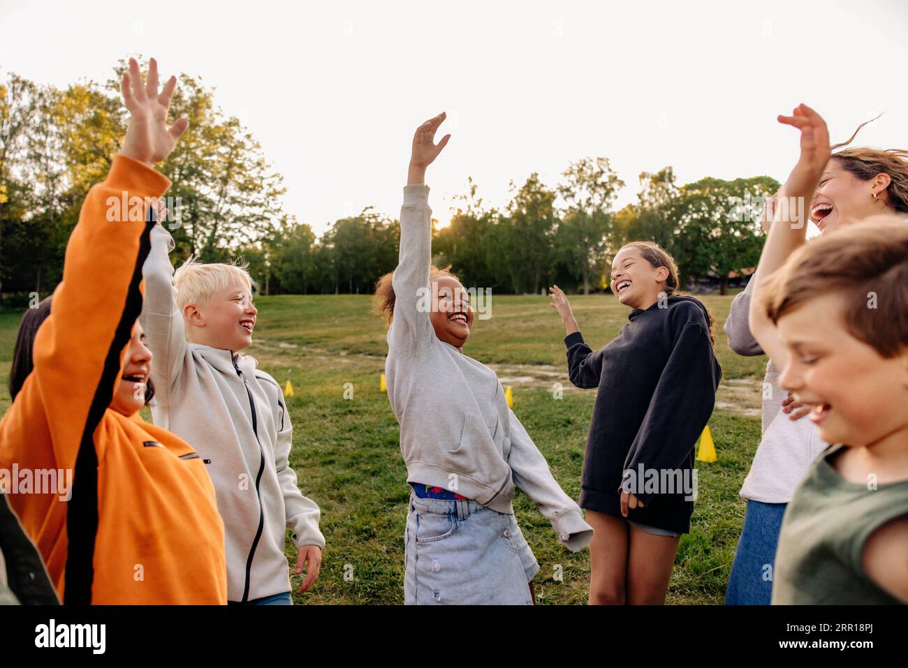 Carefree kids dancing with hand raised in playground at summer camp ...