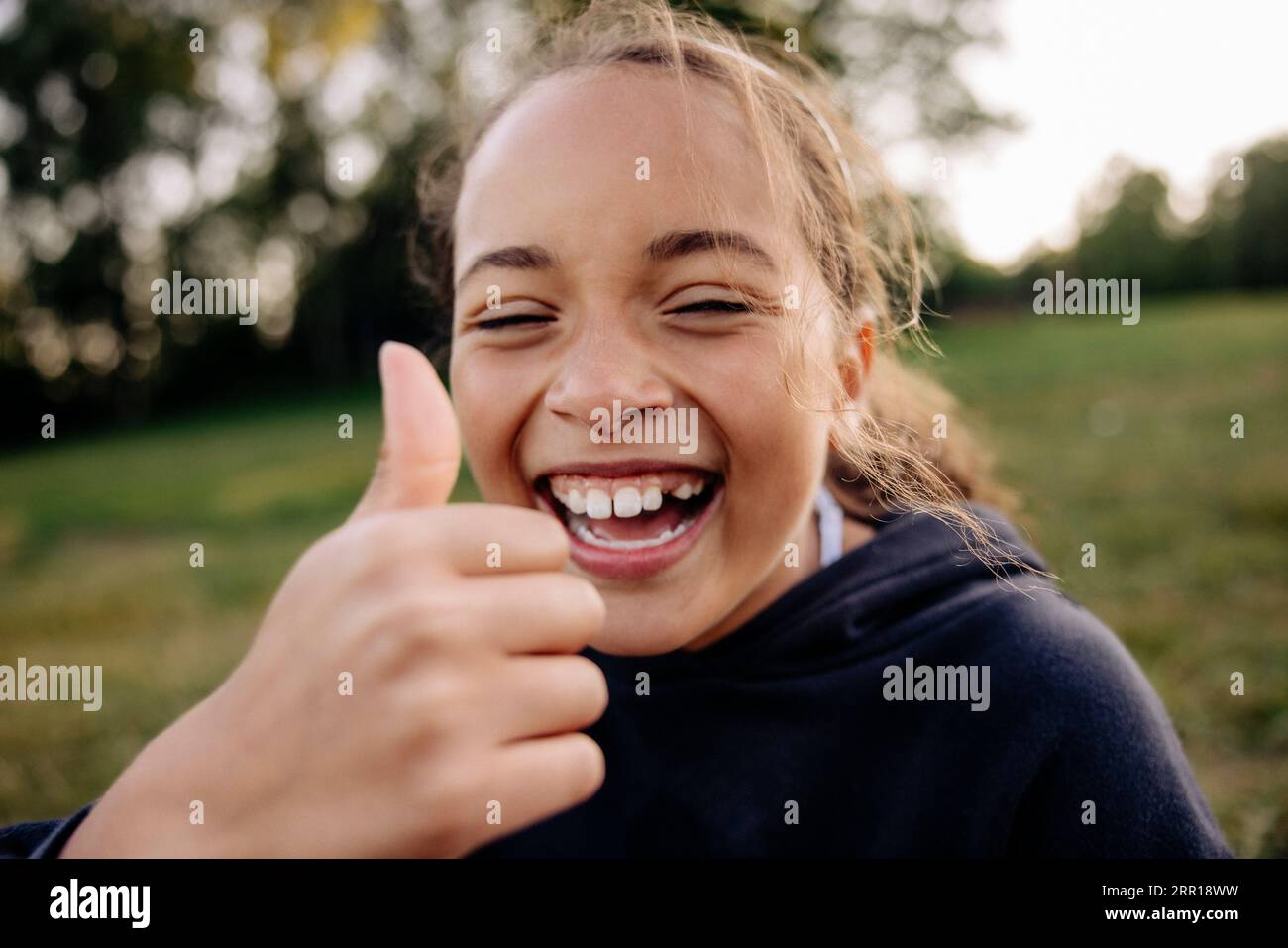 Cheerful girl showing thumbs up gesture Stock Photo - Alamy