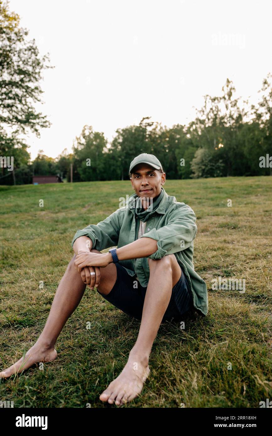 Portrait of man sitting on grass in playground Stock Photo - Alamy