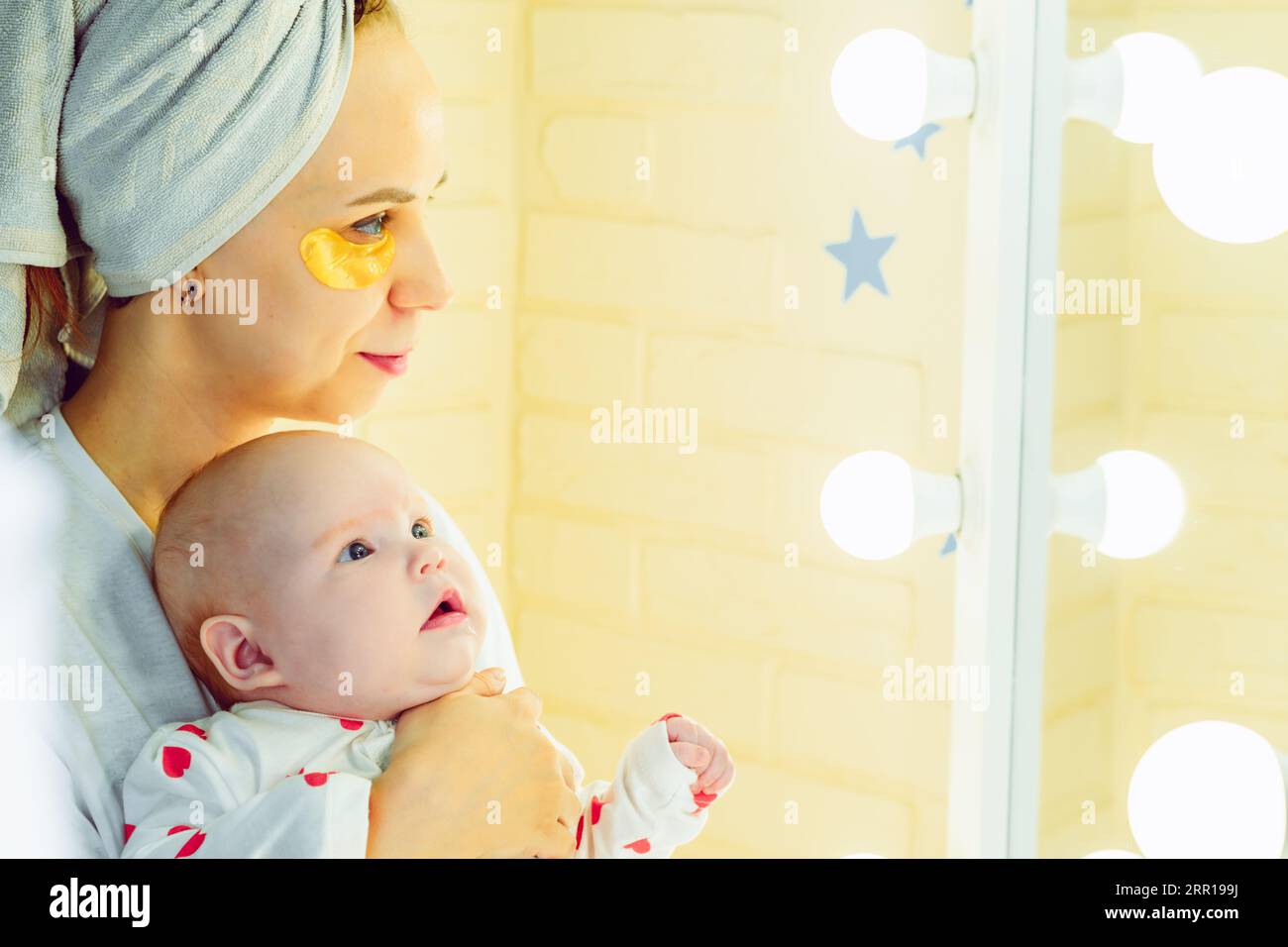 Young mother take care of her skin with under eye patches holding her ...