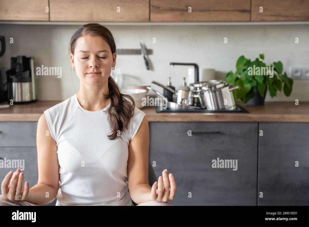 Young woman is sitting and doing meditation on background of dirty ...