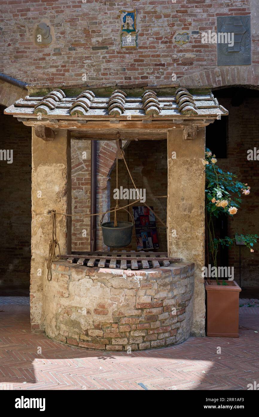 A tranquil Italian courtyard featuring a rustic well and a planter ...