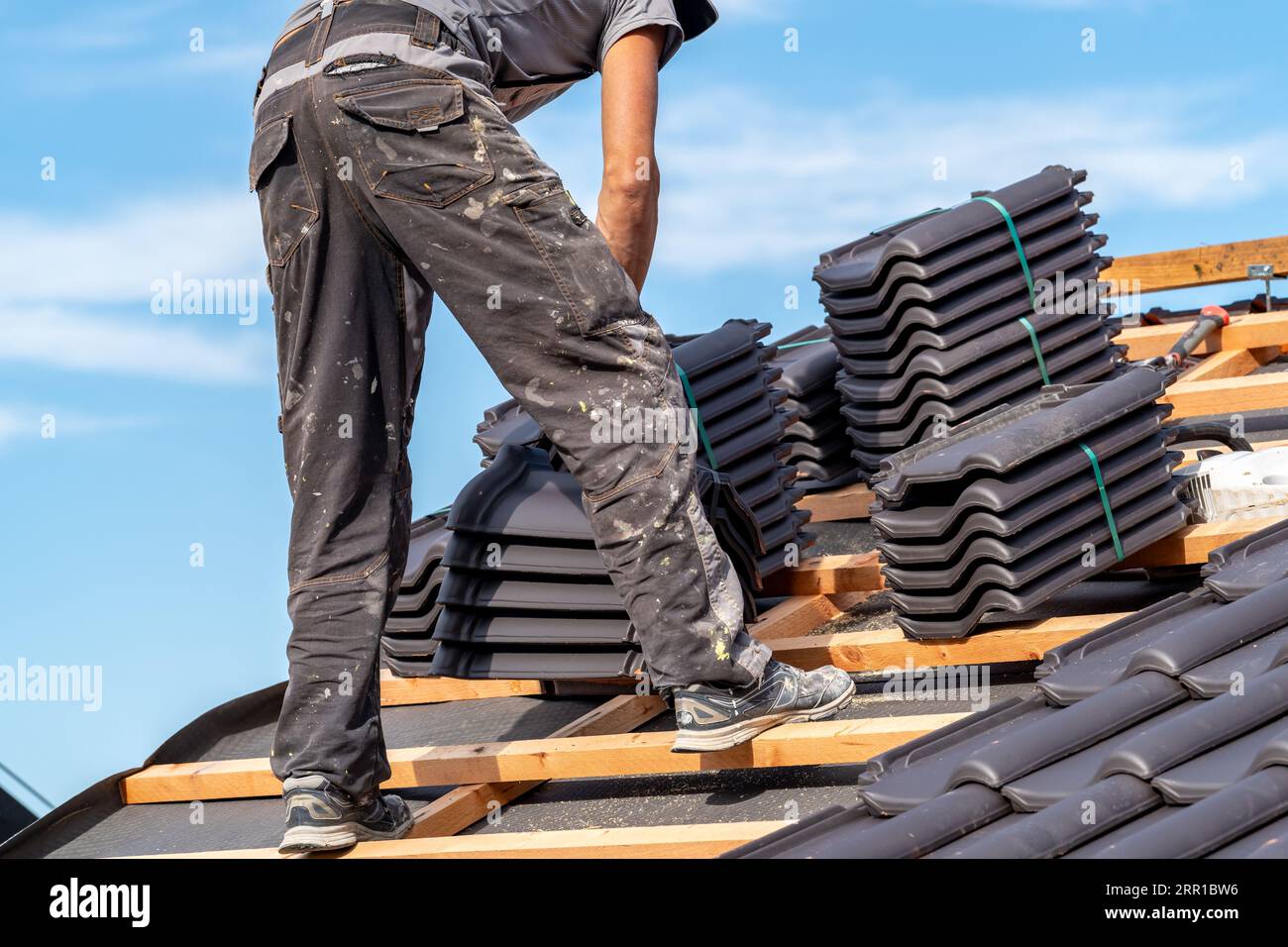 building a roof from ceramic tiles on a new family house, a craftsman ...
