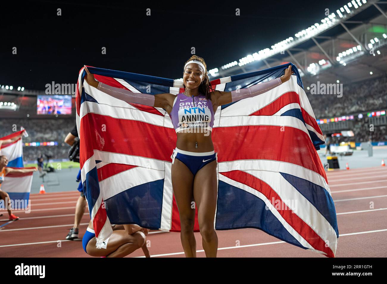 Amber Anning celebrating her medal with her country's flag in the 4x400 ...