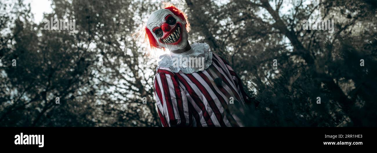a mad evil redhead clown, wearing a white and red striped costume ...