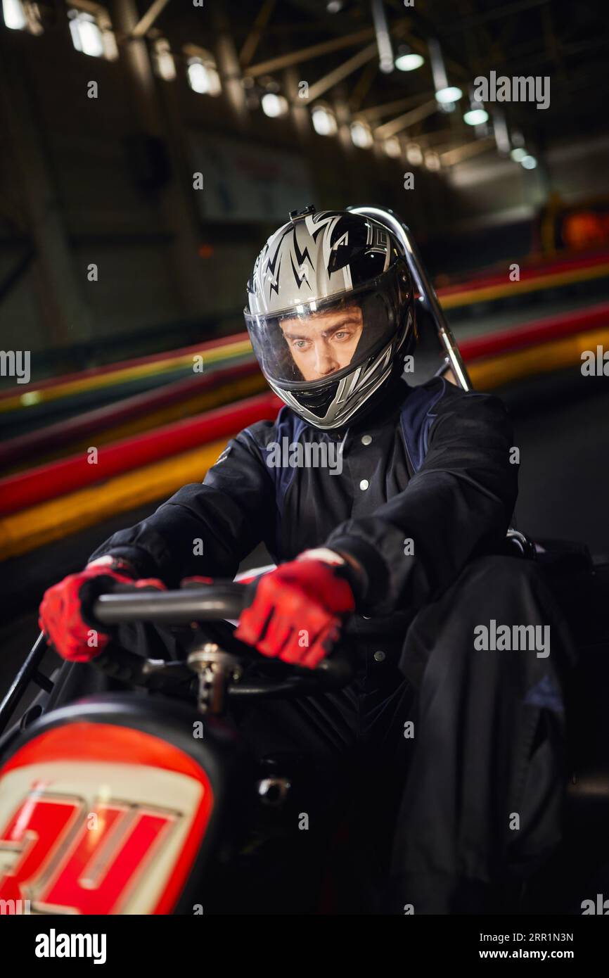 concentrated racer in helmet driving go kart car on indoor circuit ...