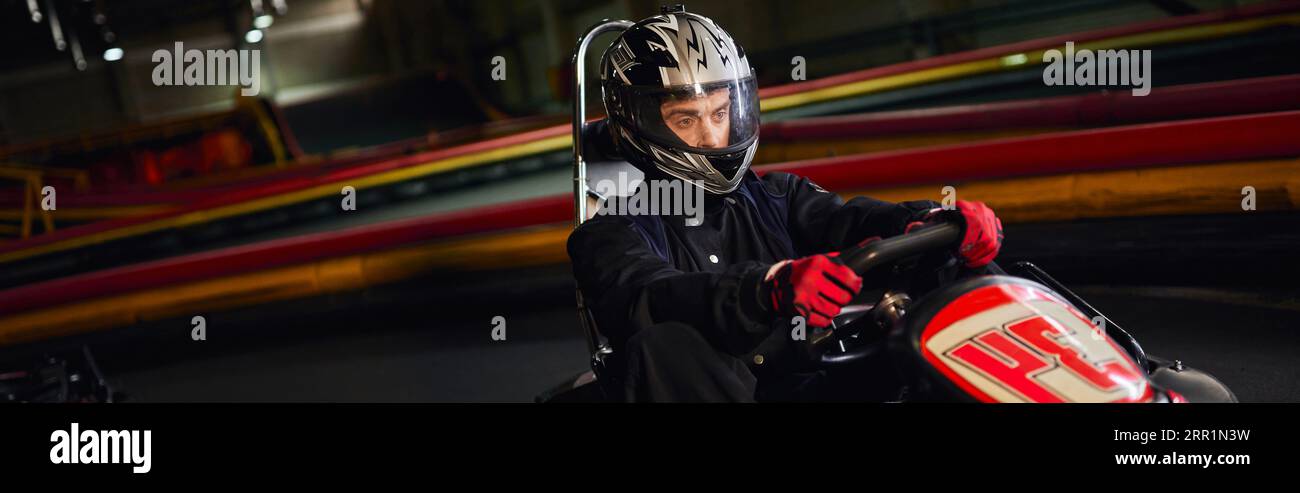 focused speed racer in helmet driving go kart car on indoor circuit ...