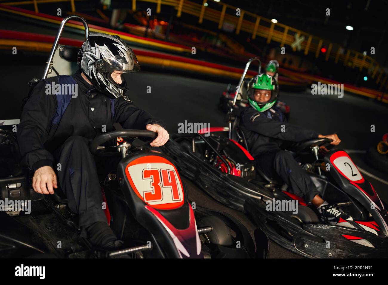 multiethnic competitors driving go kart on indoor circuit, speed racing ...