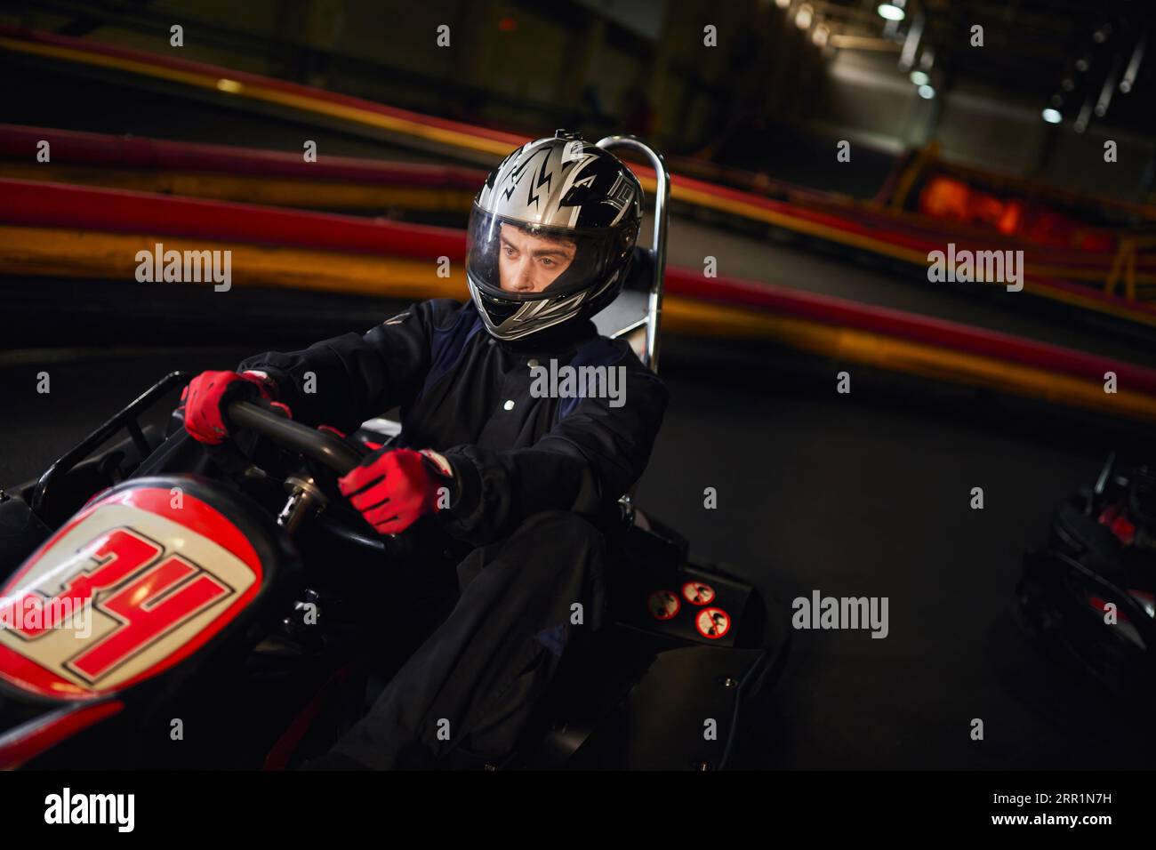 focused driver in helmet racing in go kart car on indoor circuit, speed ...