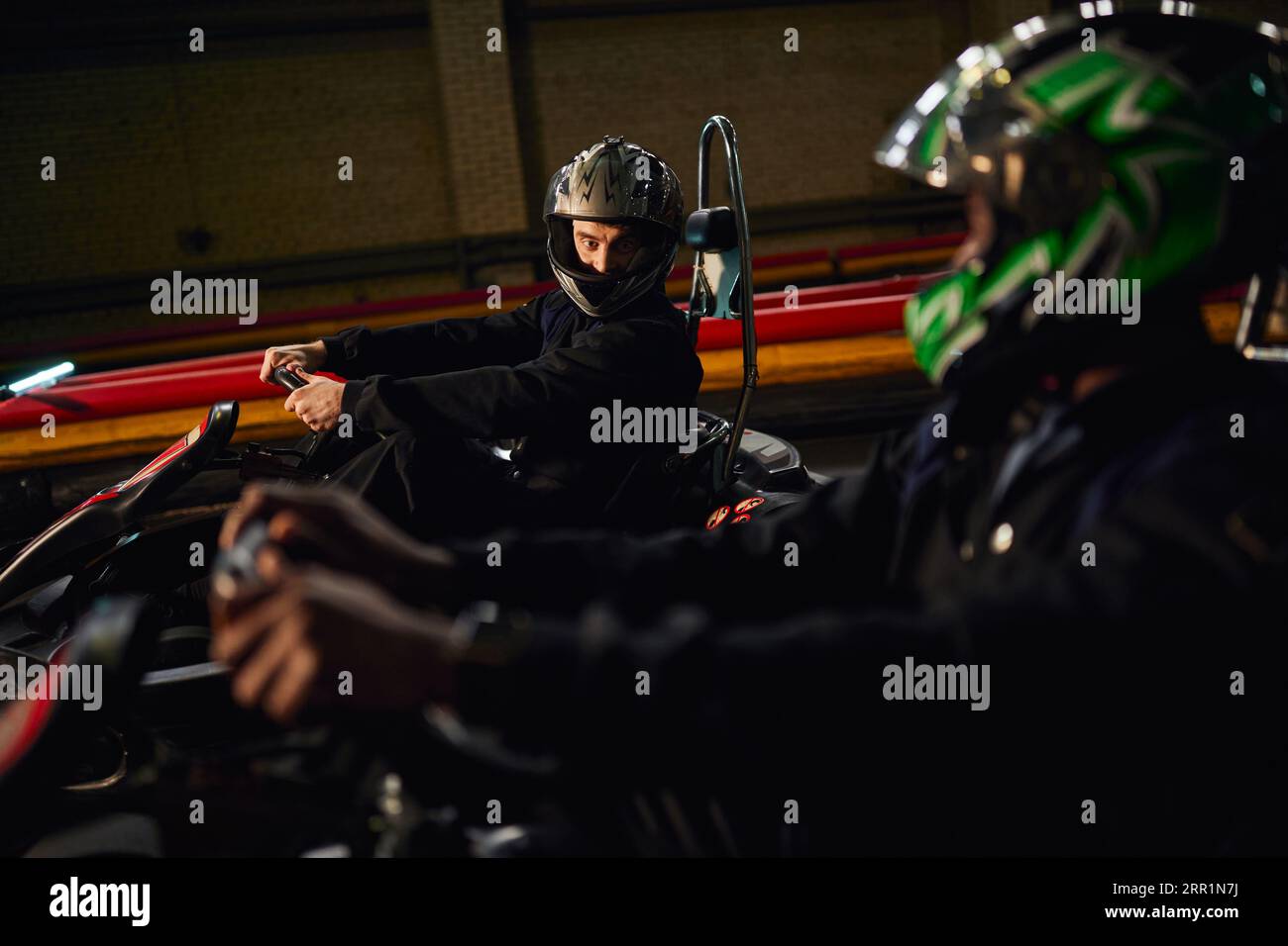 go kart driver in helmet looking at african american friend and driving ...
