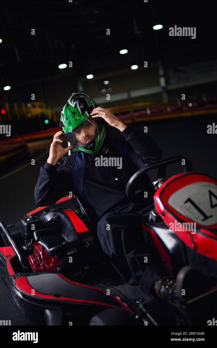 racer taking off helmet and sitting in go kart after race on indoor ...