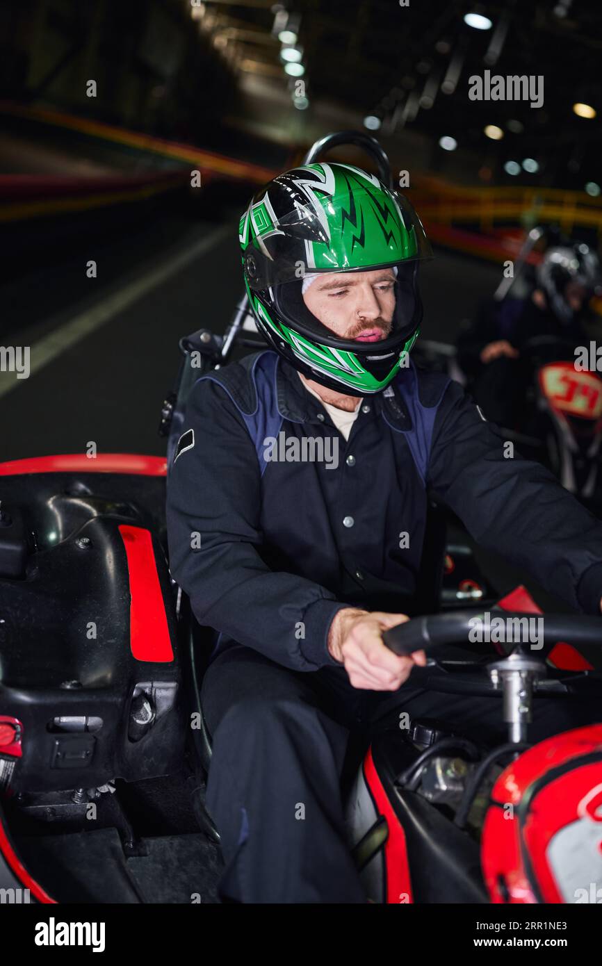 focused man in sportswear and helmet driving sport car for karting on ...