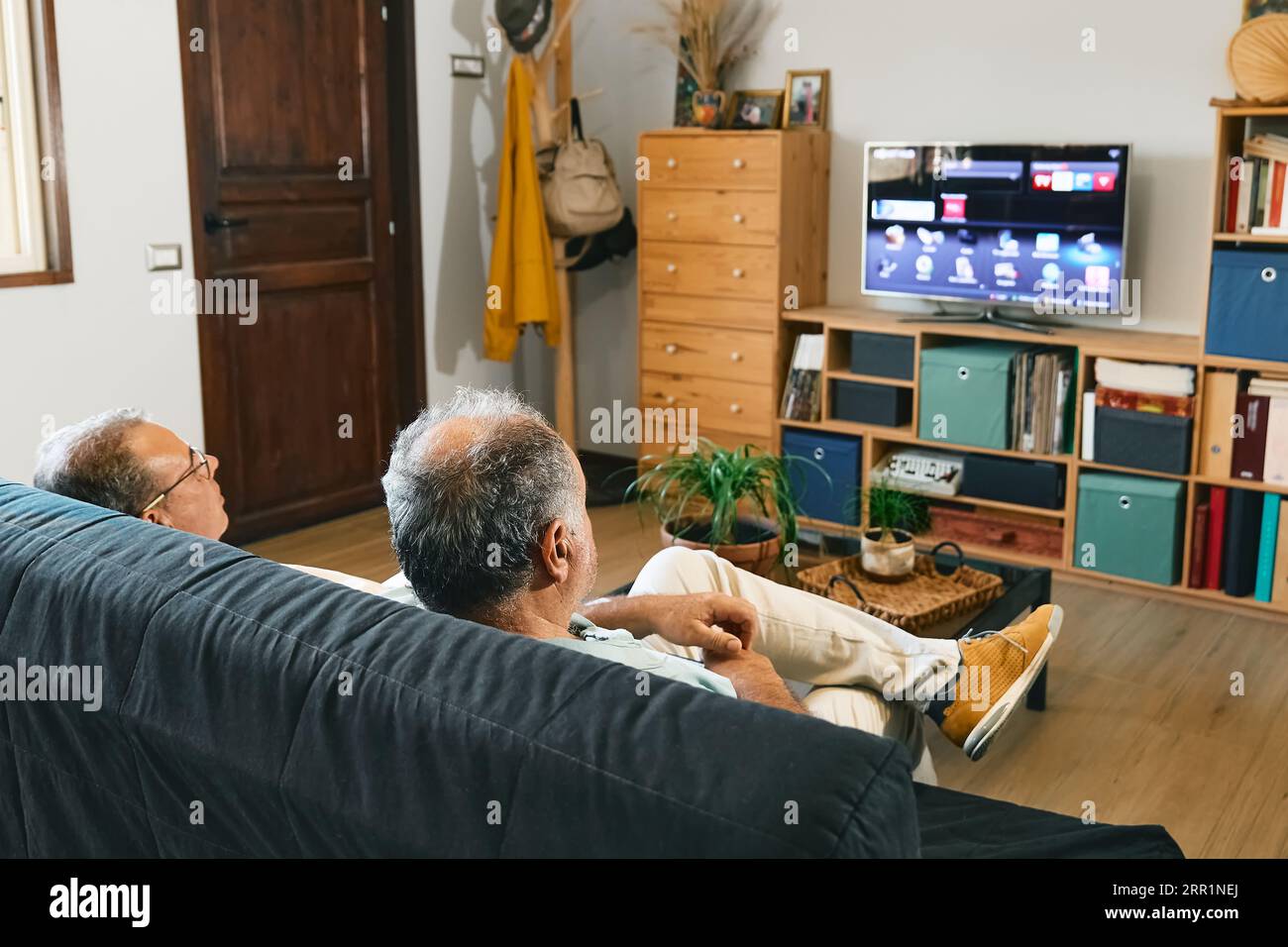 Two male friends sitting on couch watching tv, football game or ...