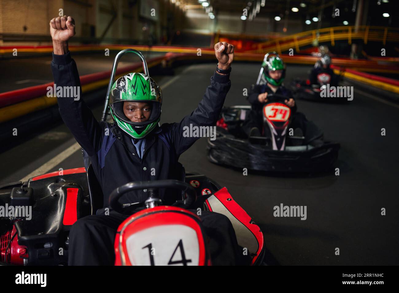 excited african american go cart racer in helmet raising hands and ...