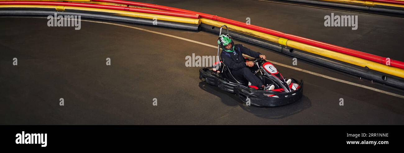african american man in go-kart on circuit, racing inside of indoor ...