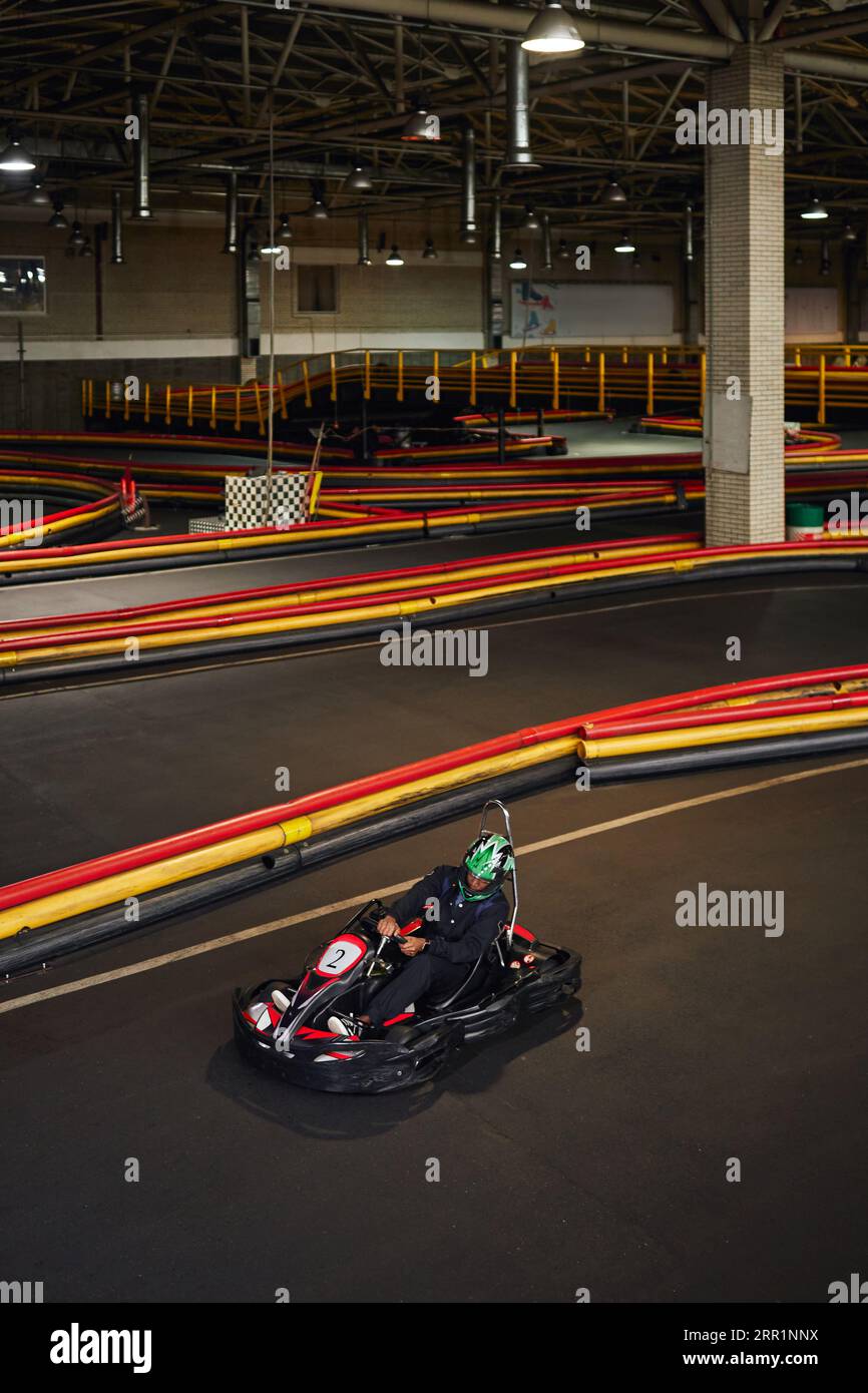 african american man in helmet in go-kart inside of indoor karting ...