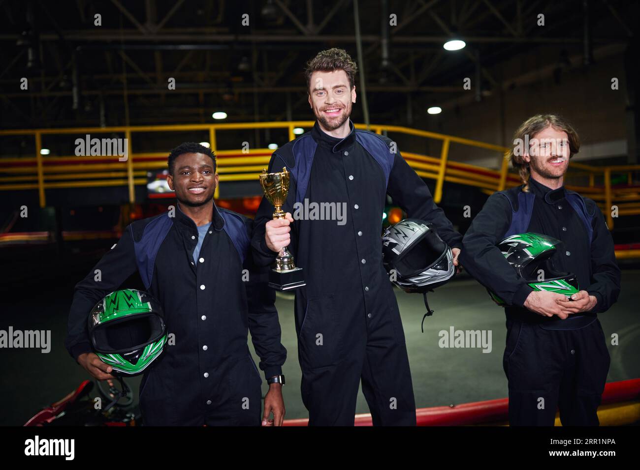 happy driver holding golden cup and standing as a winner of go-kart ...