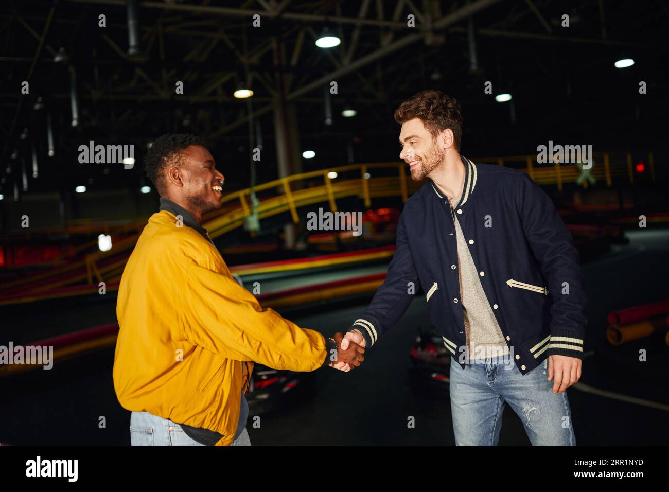 happy african american man shaking hands with friend inside of karting ...