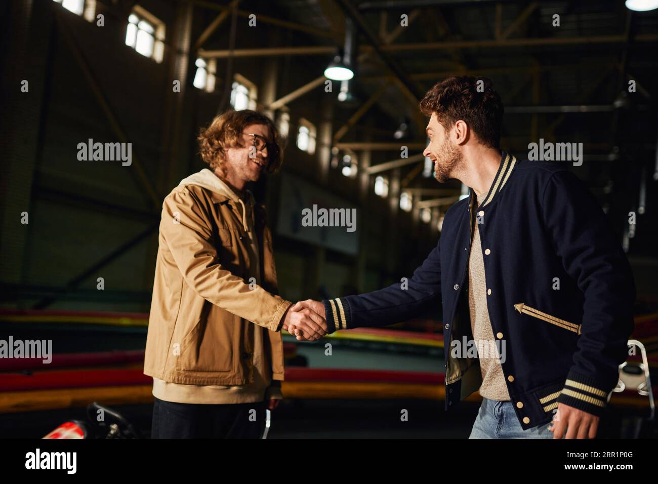 happy man in glasses shaking hands with joyful friend inside of karting ...
