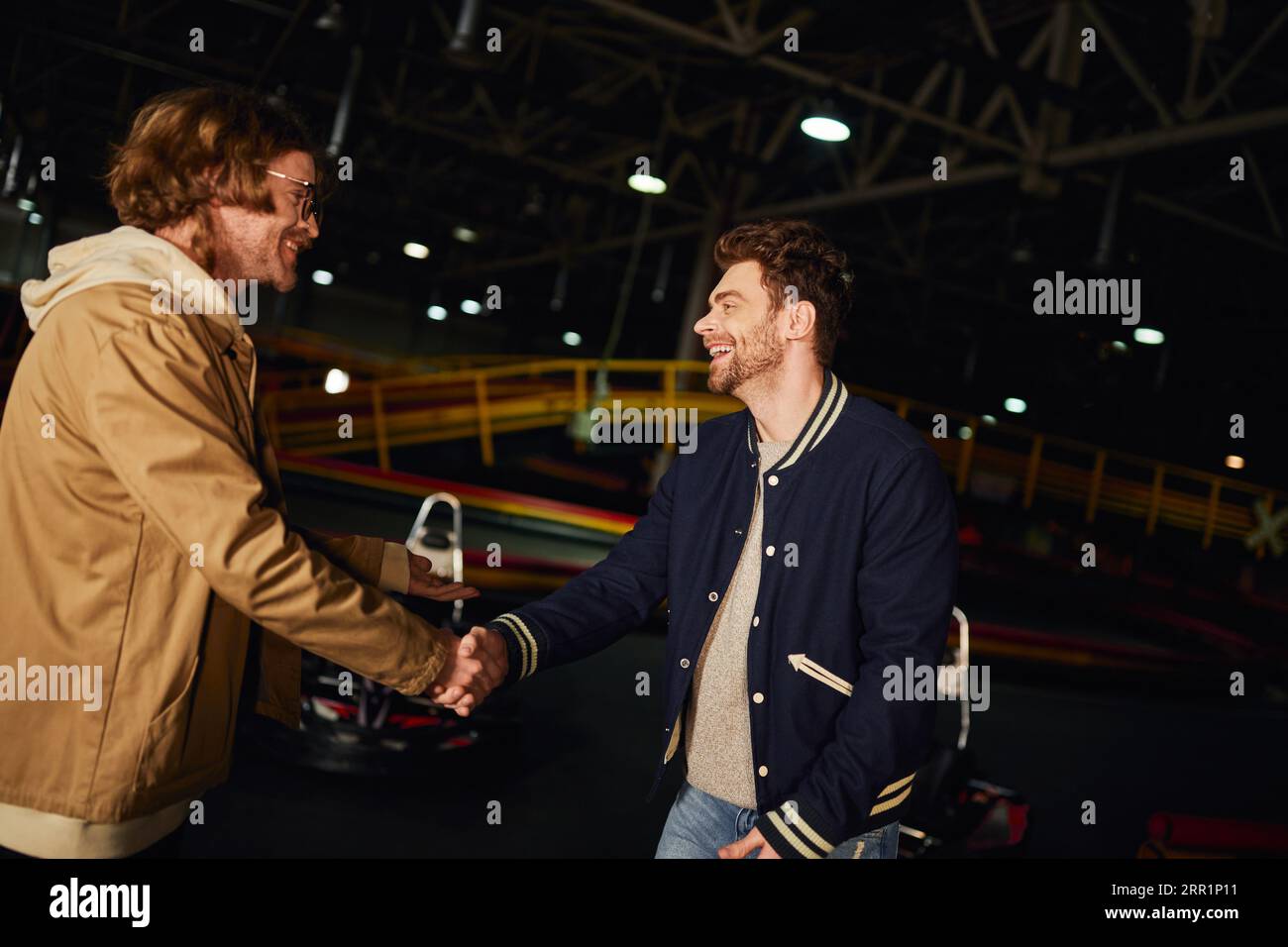 happy man in glasses shaking hands with friend inside of karting racing ...