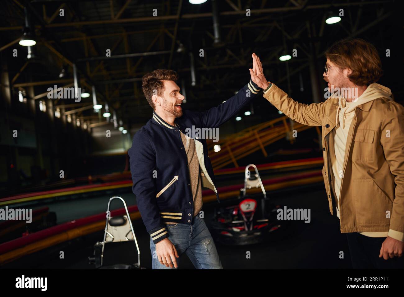 happy male friends giving high five to each other inside of karting ...