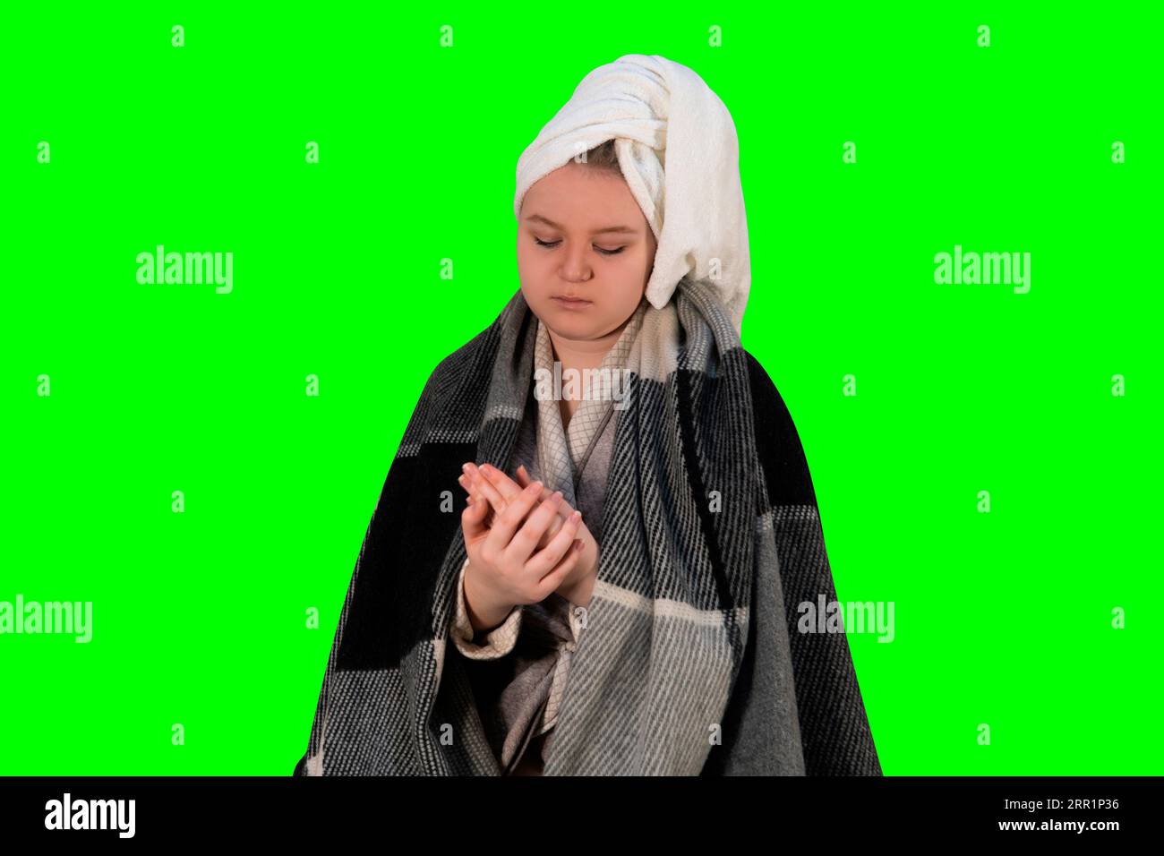 A girl with cold symptoms disinfects her hands on a green background ...