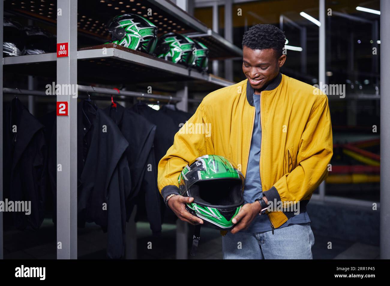 happy african american kart racer in yellow bomber jacket holding ...
