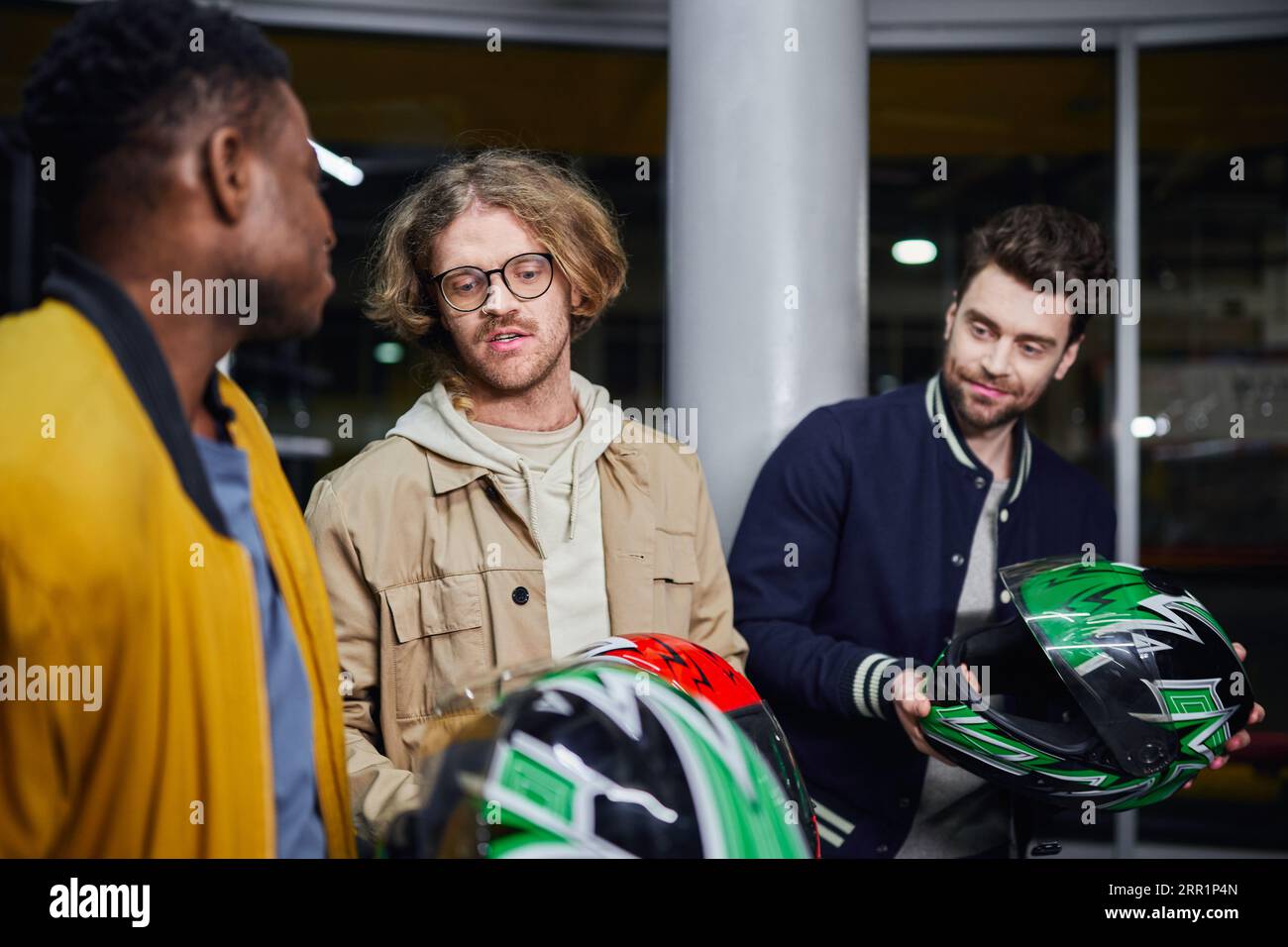 men with helmets chatting with african american friend inside of indoor ...