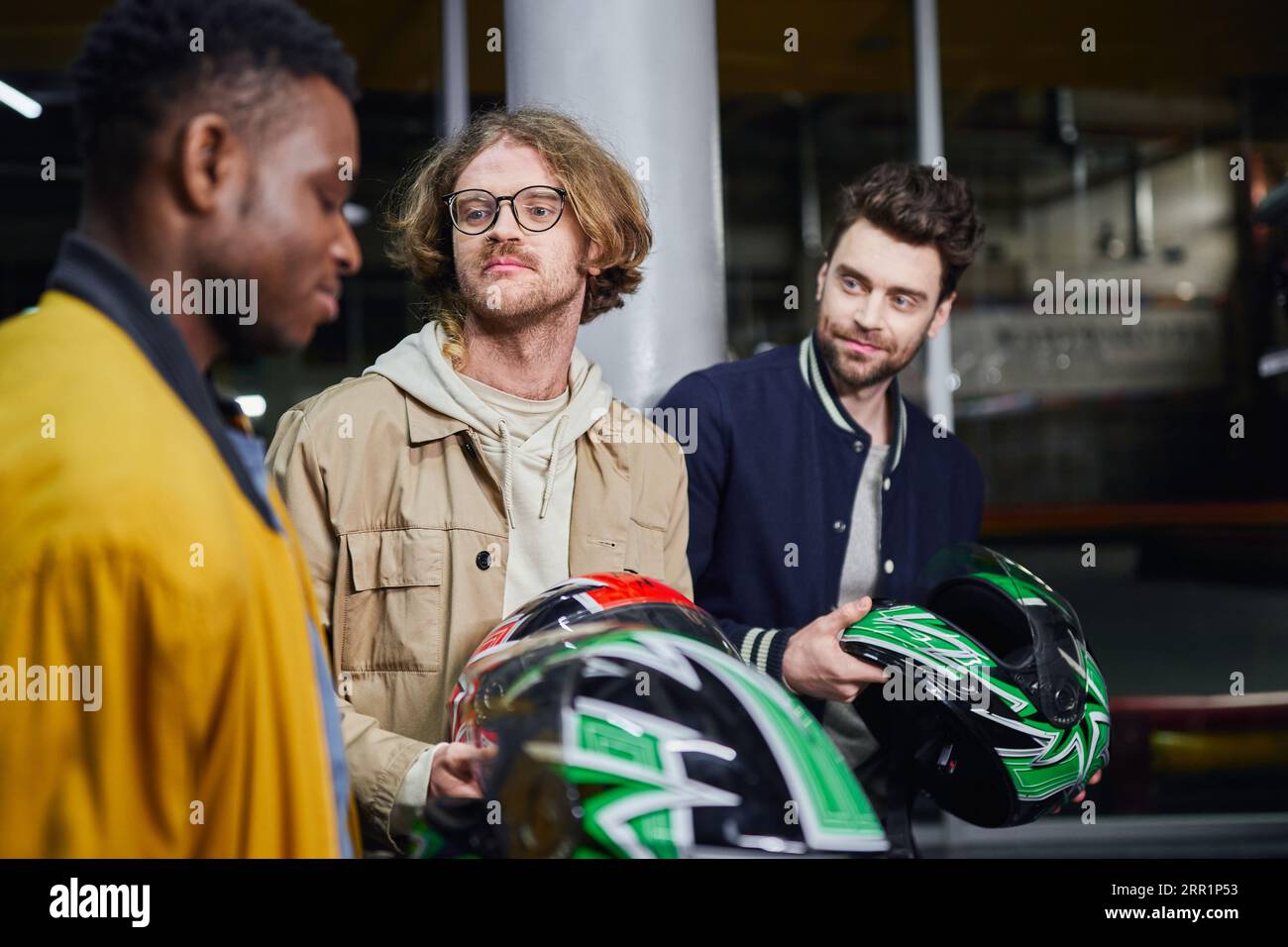 men with helmets looking at african american friend inside of indoor ...