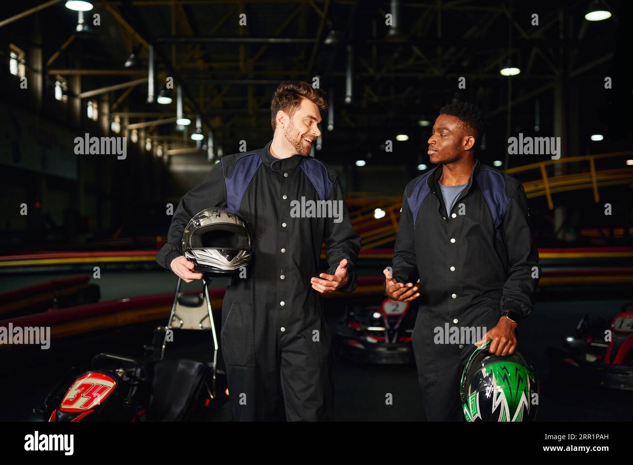 happy multicultural men chatting inside of kart circuit, kart racers ...