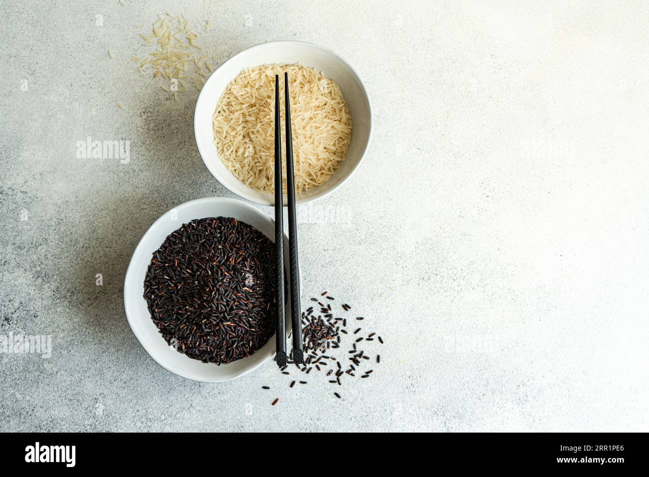 Top view of Raw wild black rice and peeled white rice in the bowls with ...