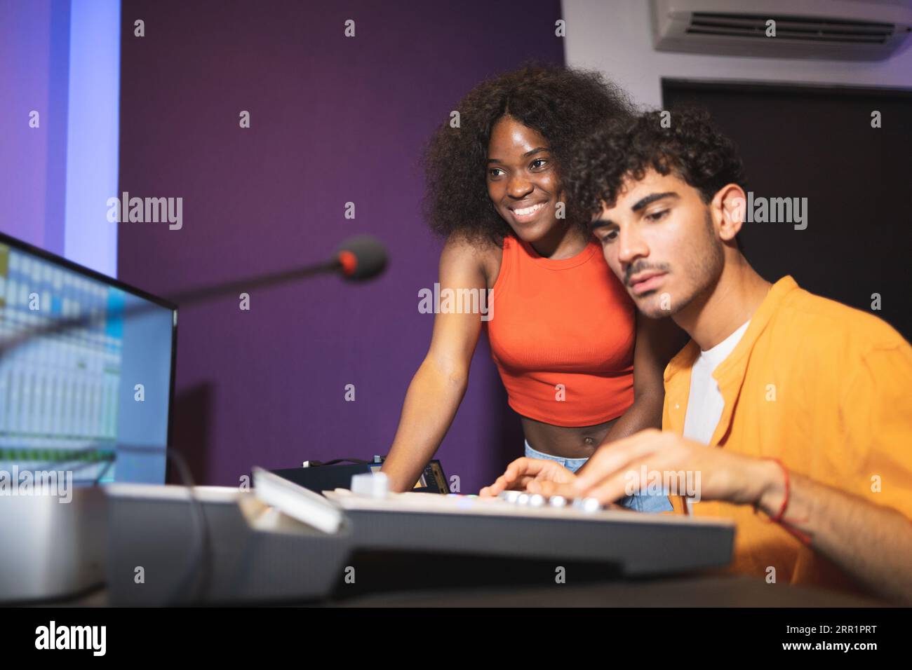 Male audio engineer and joyful female African American singer creating ...