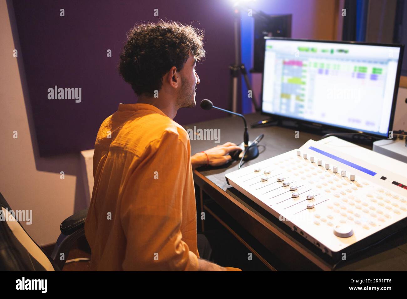 Side view of male audio engineer using mixing board and computer sound ...