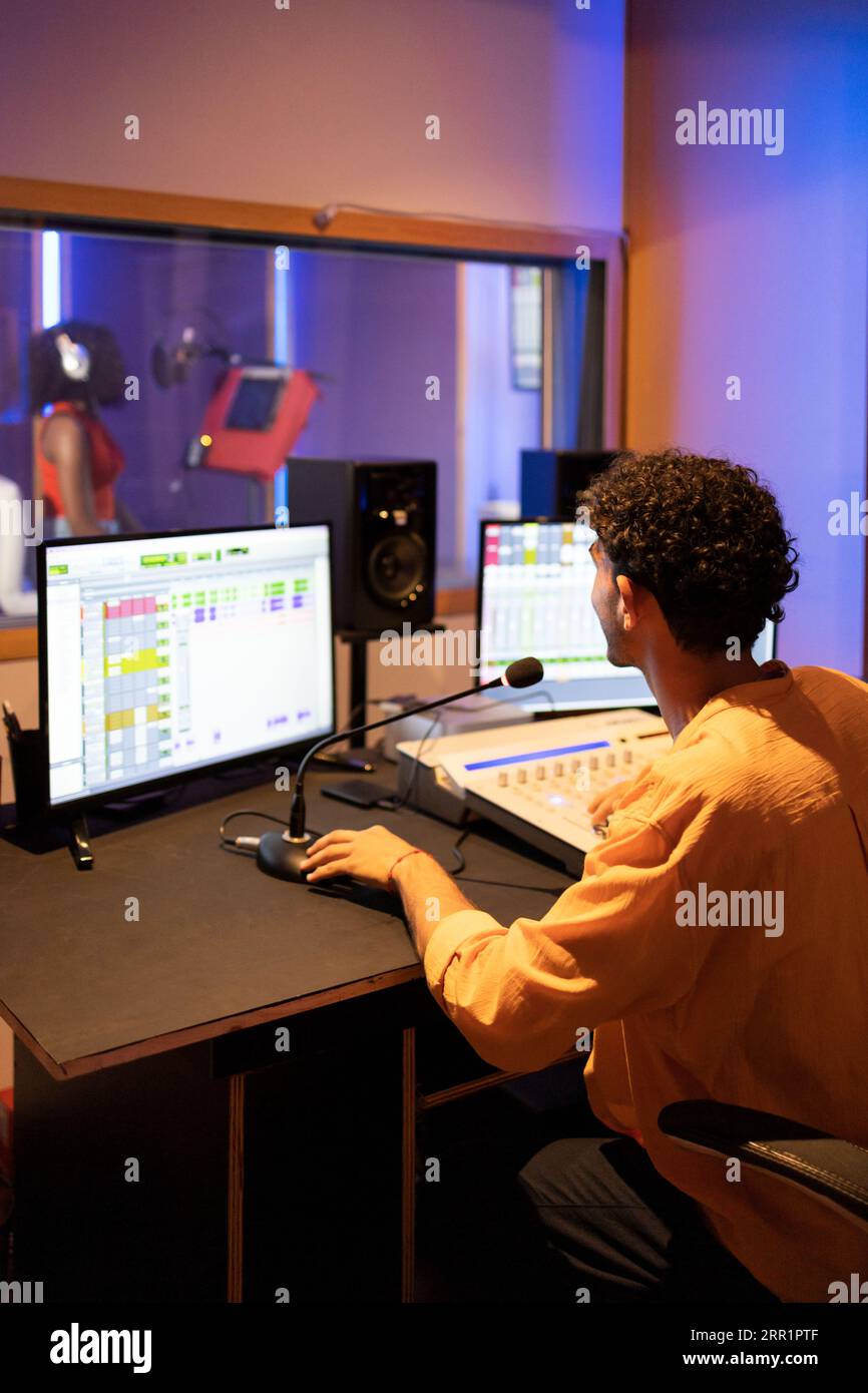 Faceless male audio engineer with mixing board and computer showing ...