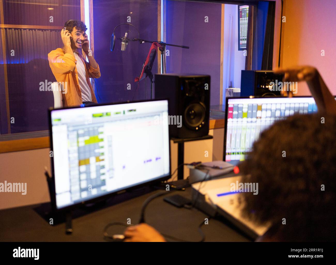Back view of crop African American female audio engineer using mixing board and sound software ...