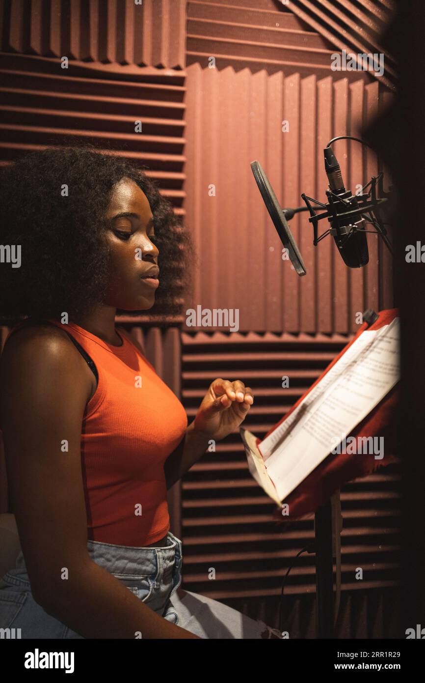 Side view of focused young African American female singer looking down ...