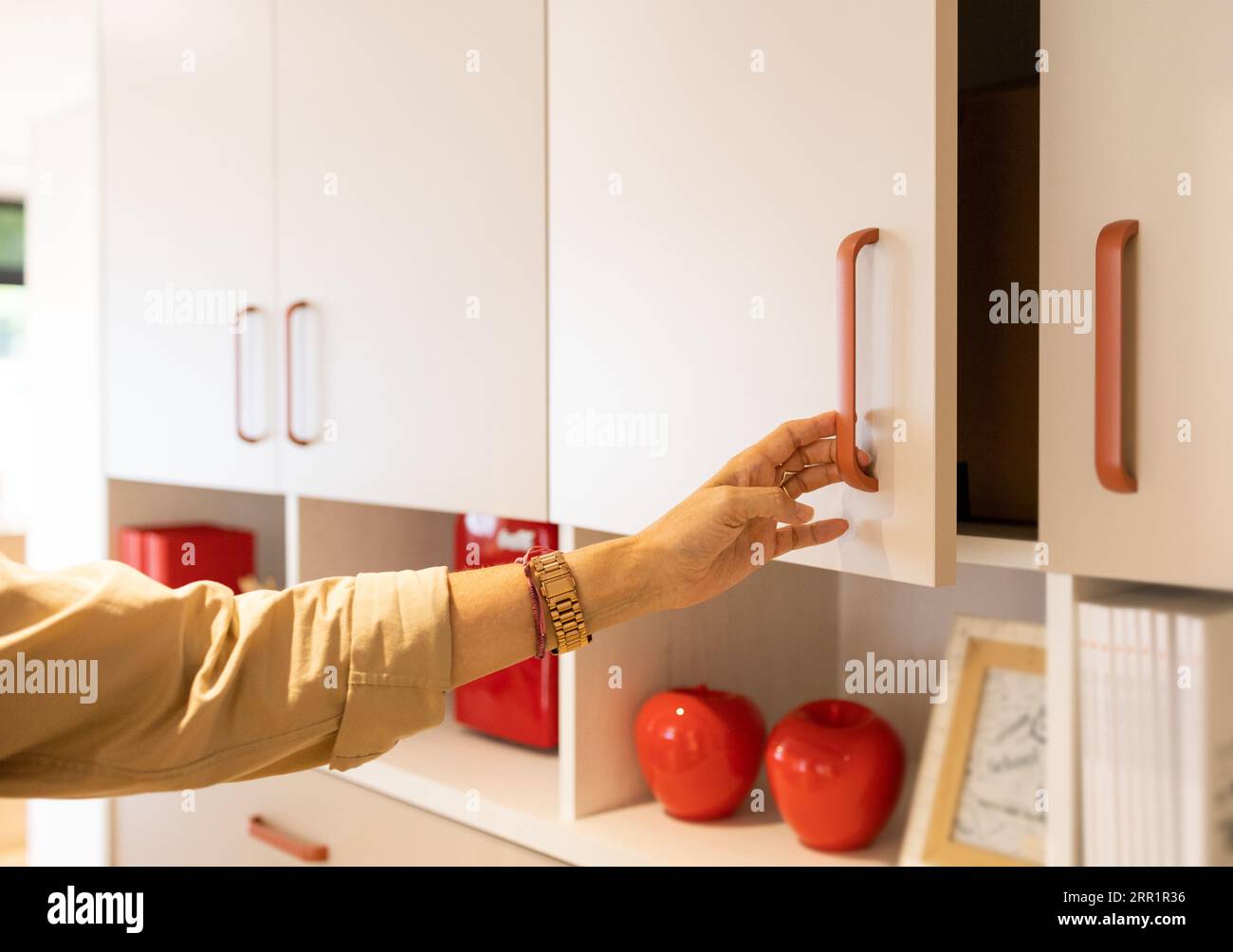 Crop anonymous woman showing wooden kitchen cabinet with utensils and ...