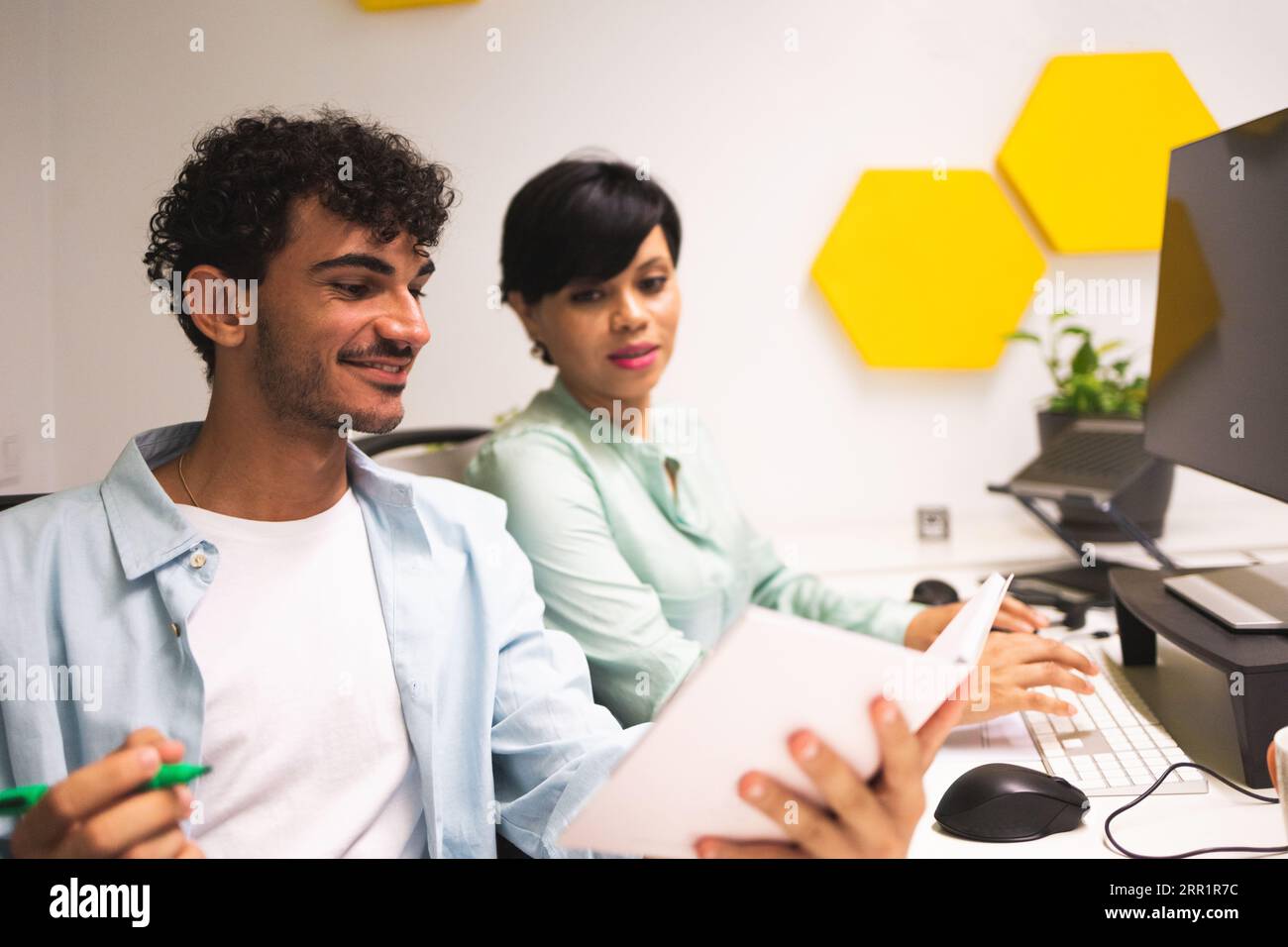 Smiling young multiracial colleagues looking down while sitting at ...