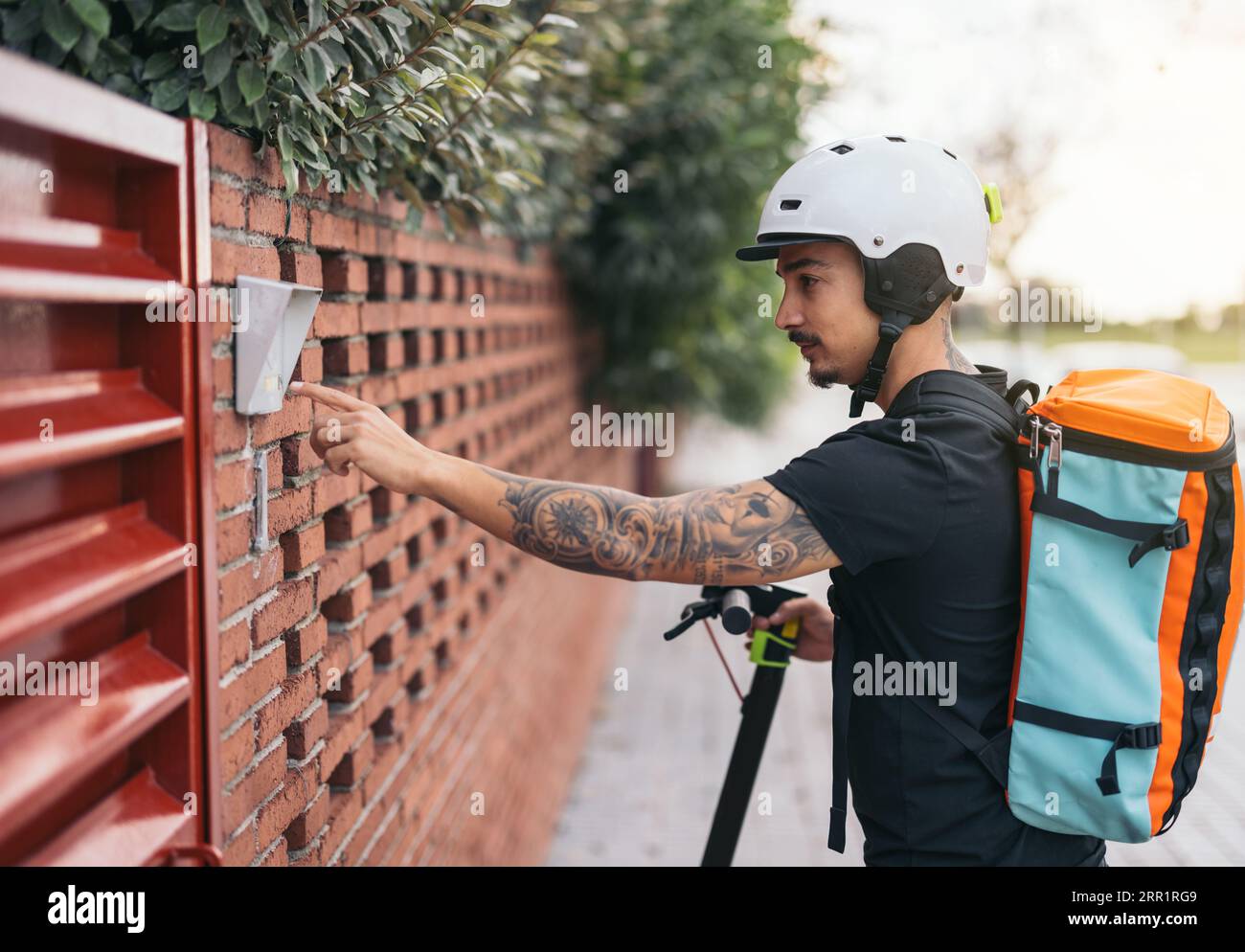 Side view of young delivery man in helmet with thermal backpack on ...