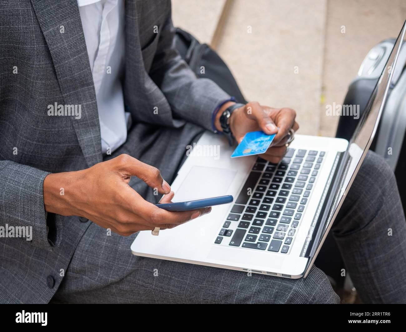 High angle of cropped unrecognizable African American male in formal wear using cellphone for ...