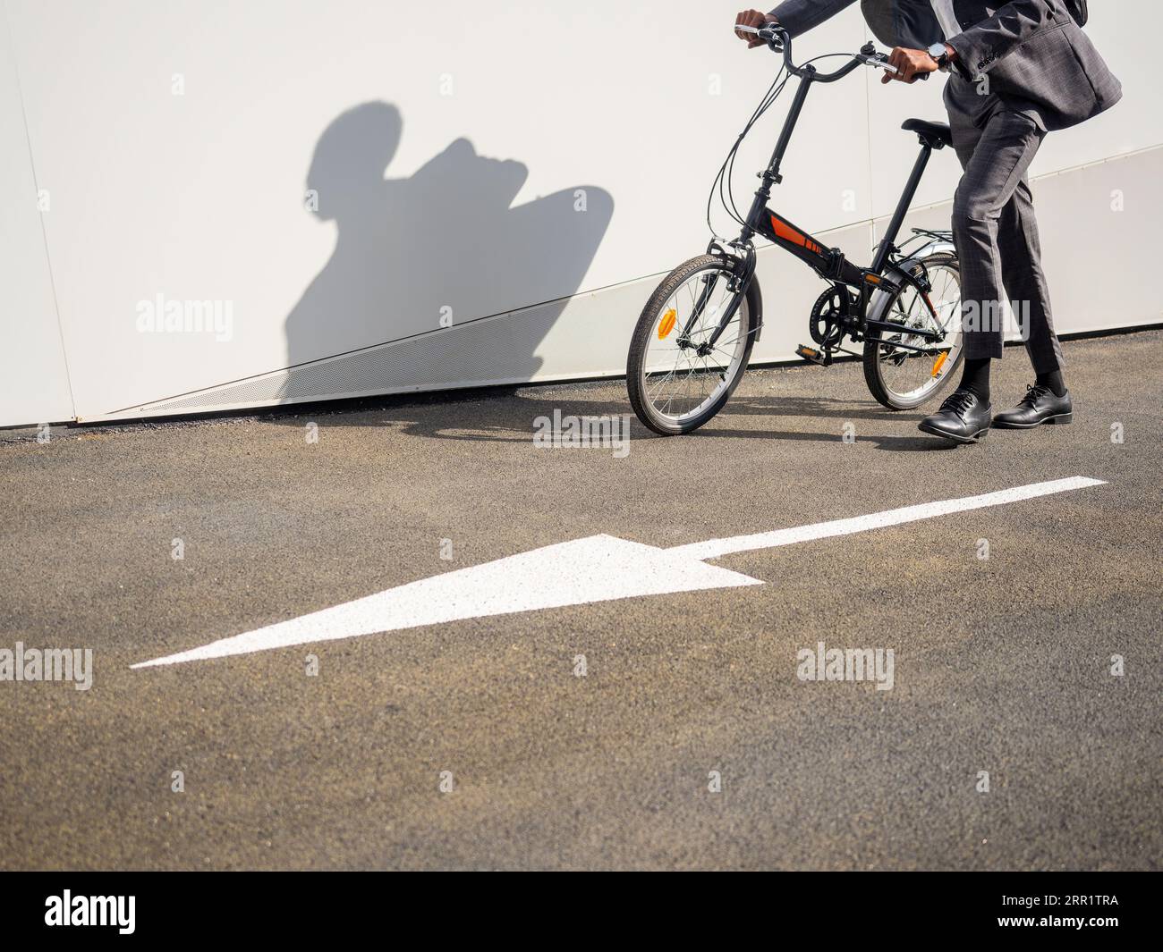 Side view of cropped anonymous person riding bicycle along asphalt road ...