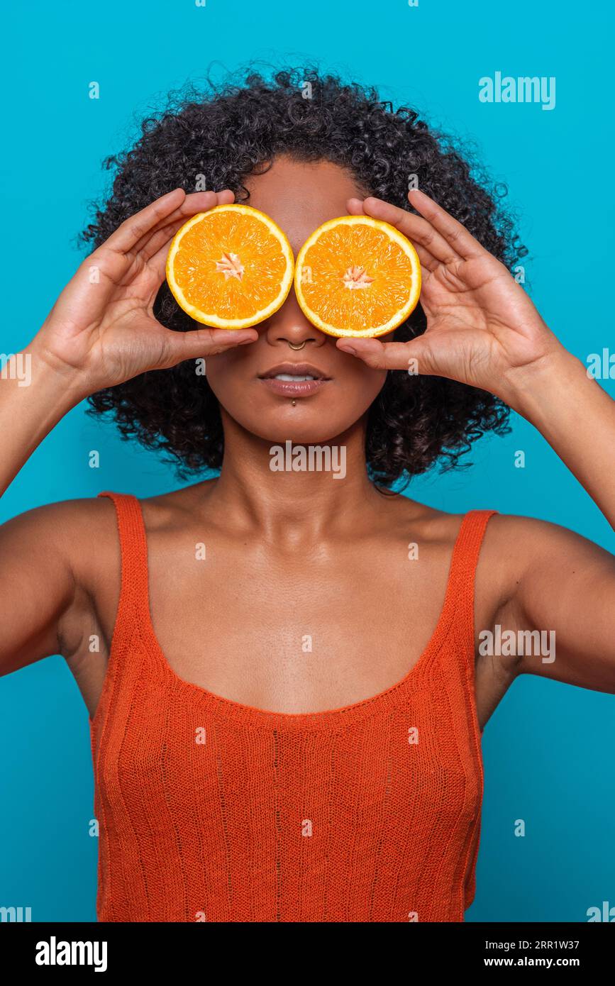 Serious young Hispanic female with curly hair covering eyes with slice ...