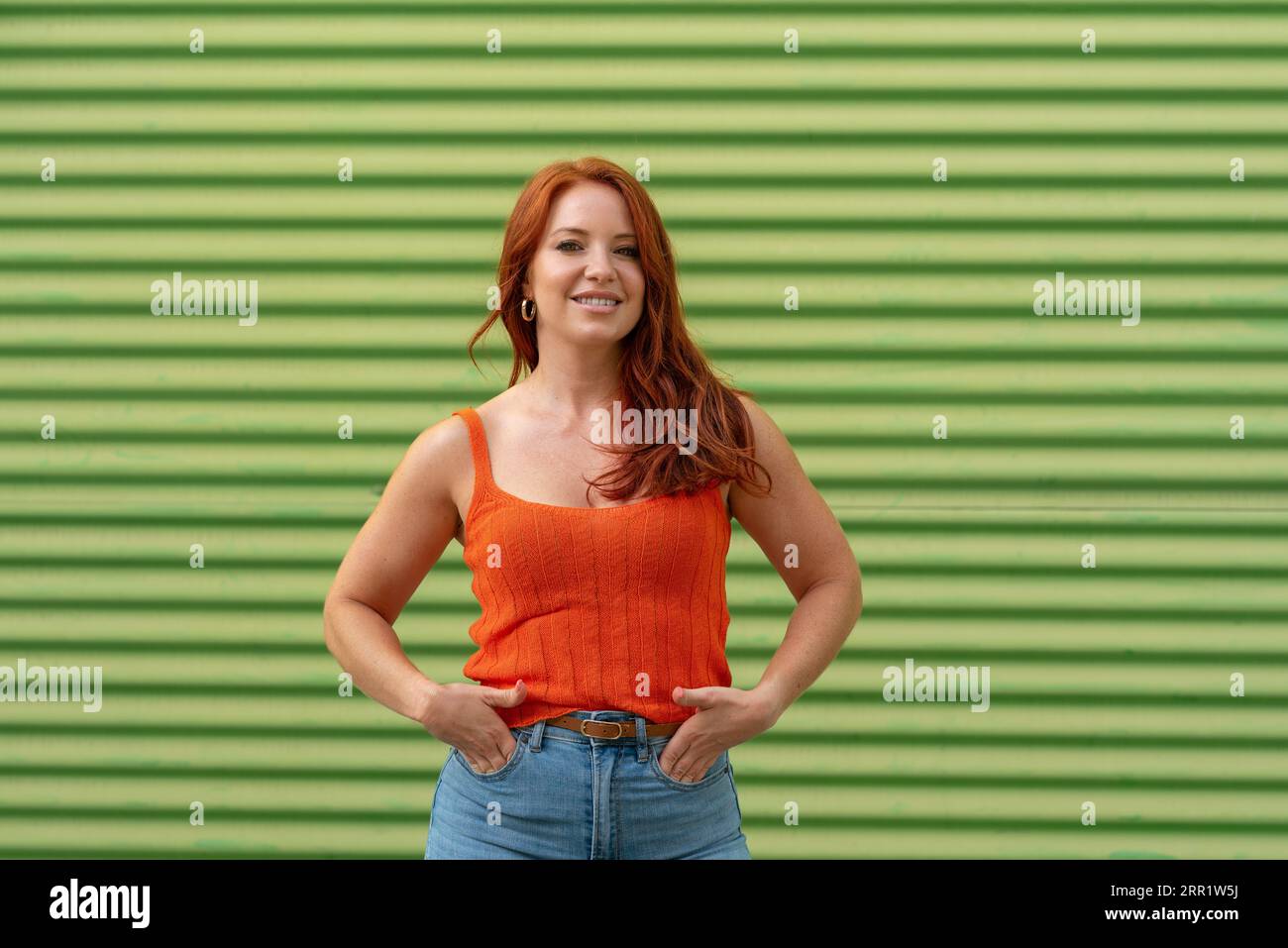 Positive young female with long ginger hair smiling and looking at ...